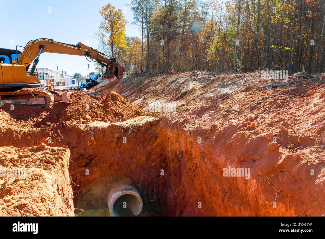 Heavy excavator digs trench for drainage pipe at construction site ...