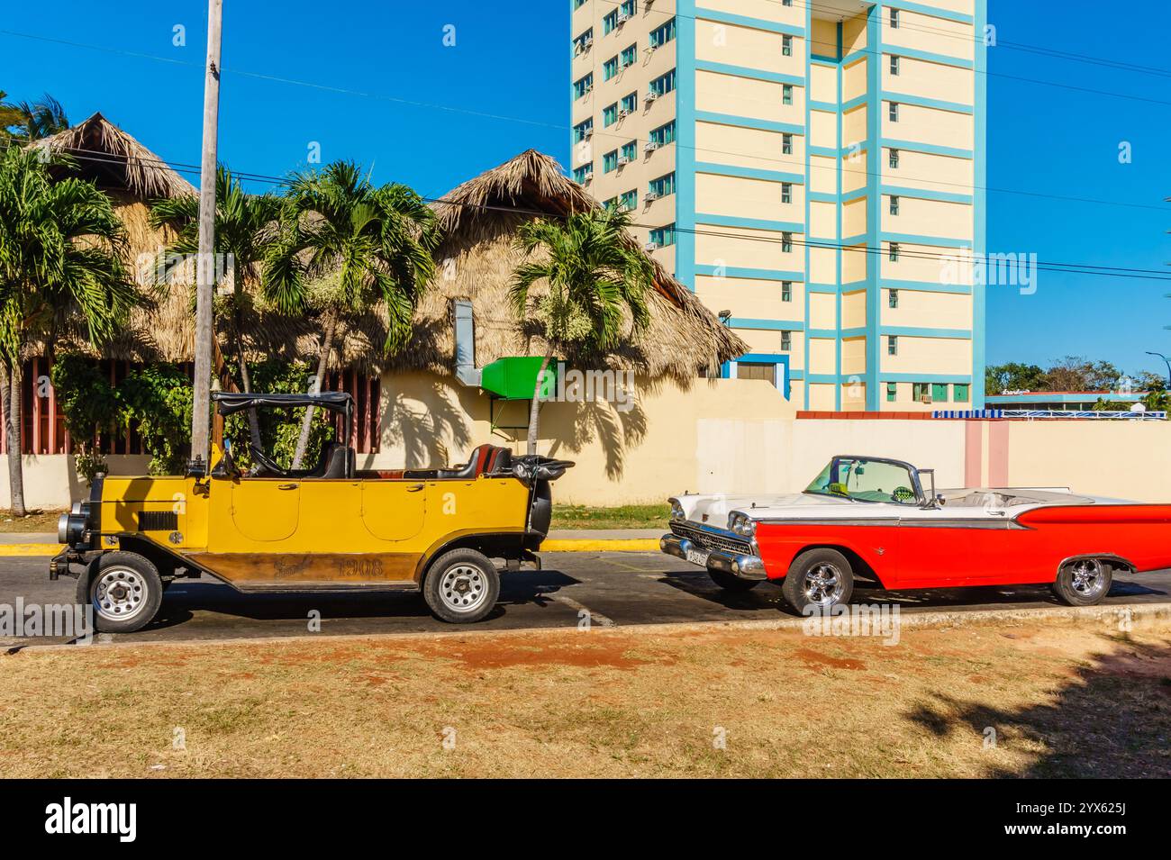 Two cars, one yellow and one red, are parked next to each other on a ...