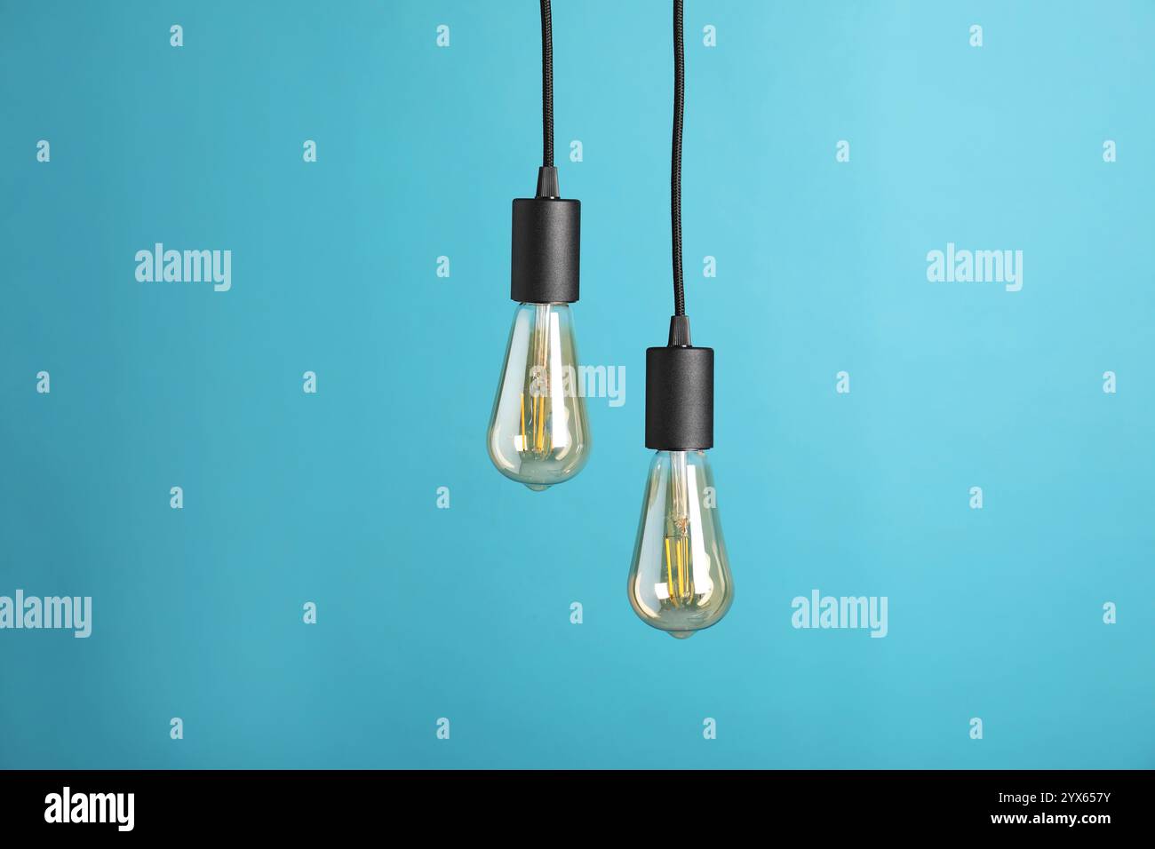 Light bulbs hanging on cords against light blue background Stock Photo ...