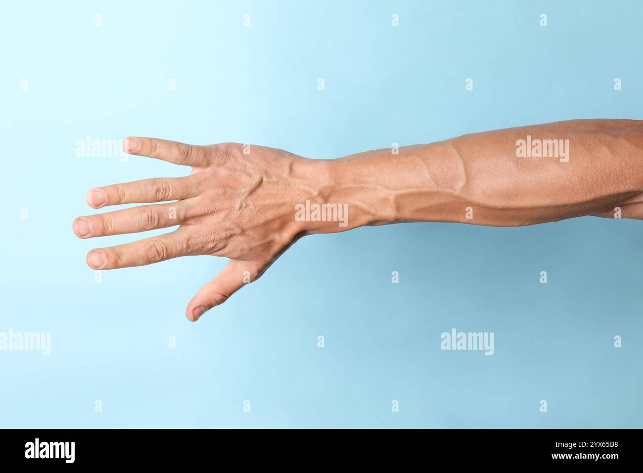 Man with bulging veins on his arm against light blue background ...