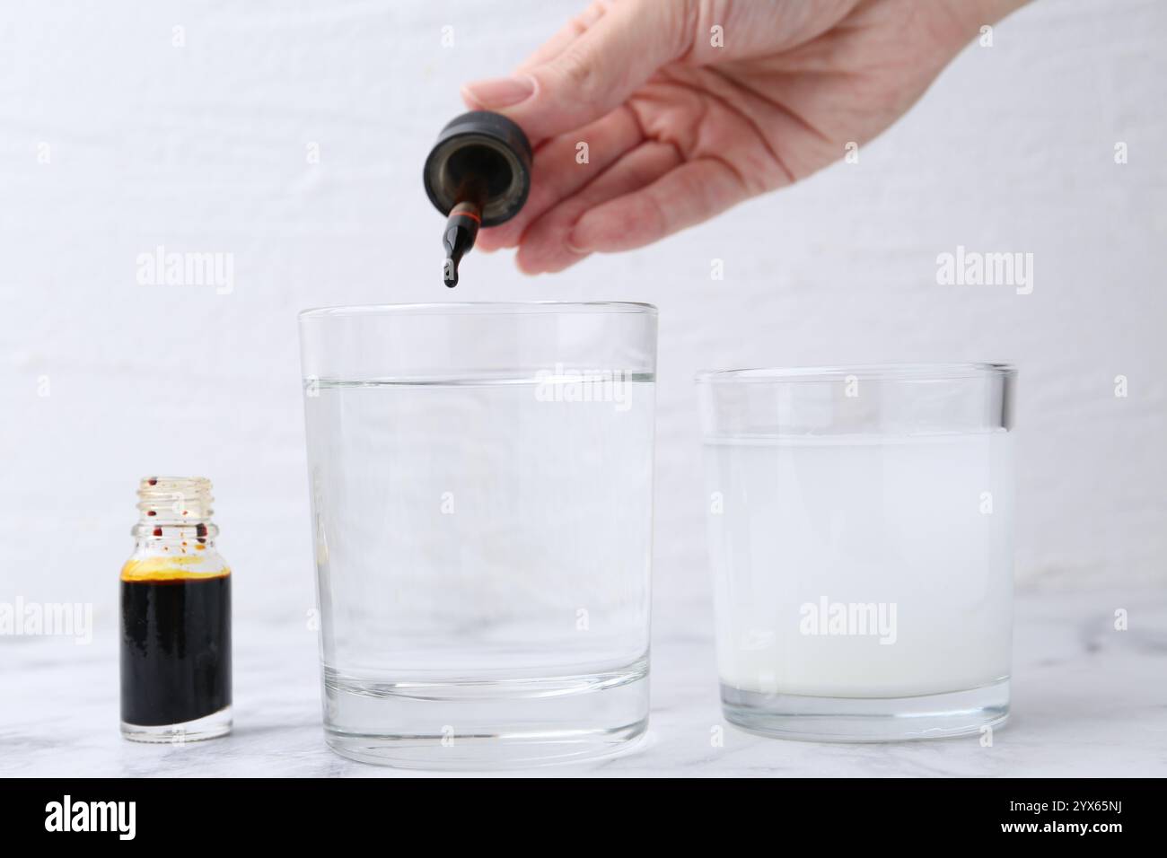 Iodine starch test. Woman dripping aqueous iodine into glass of water ...