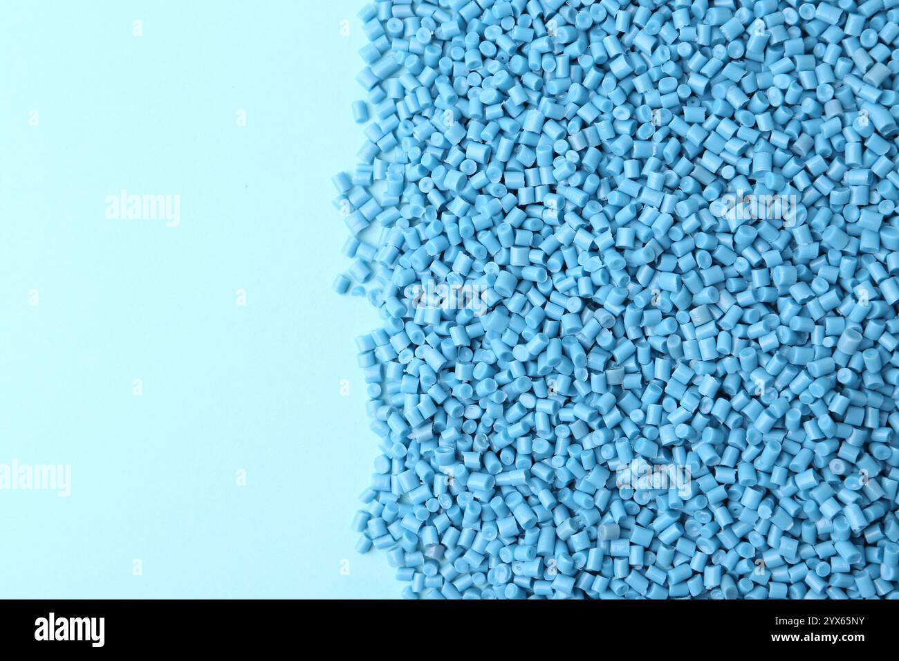 Pile of plastic granules on light blue background, top view. Space for ...