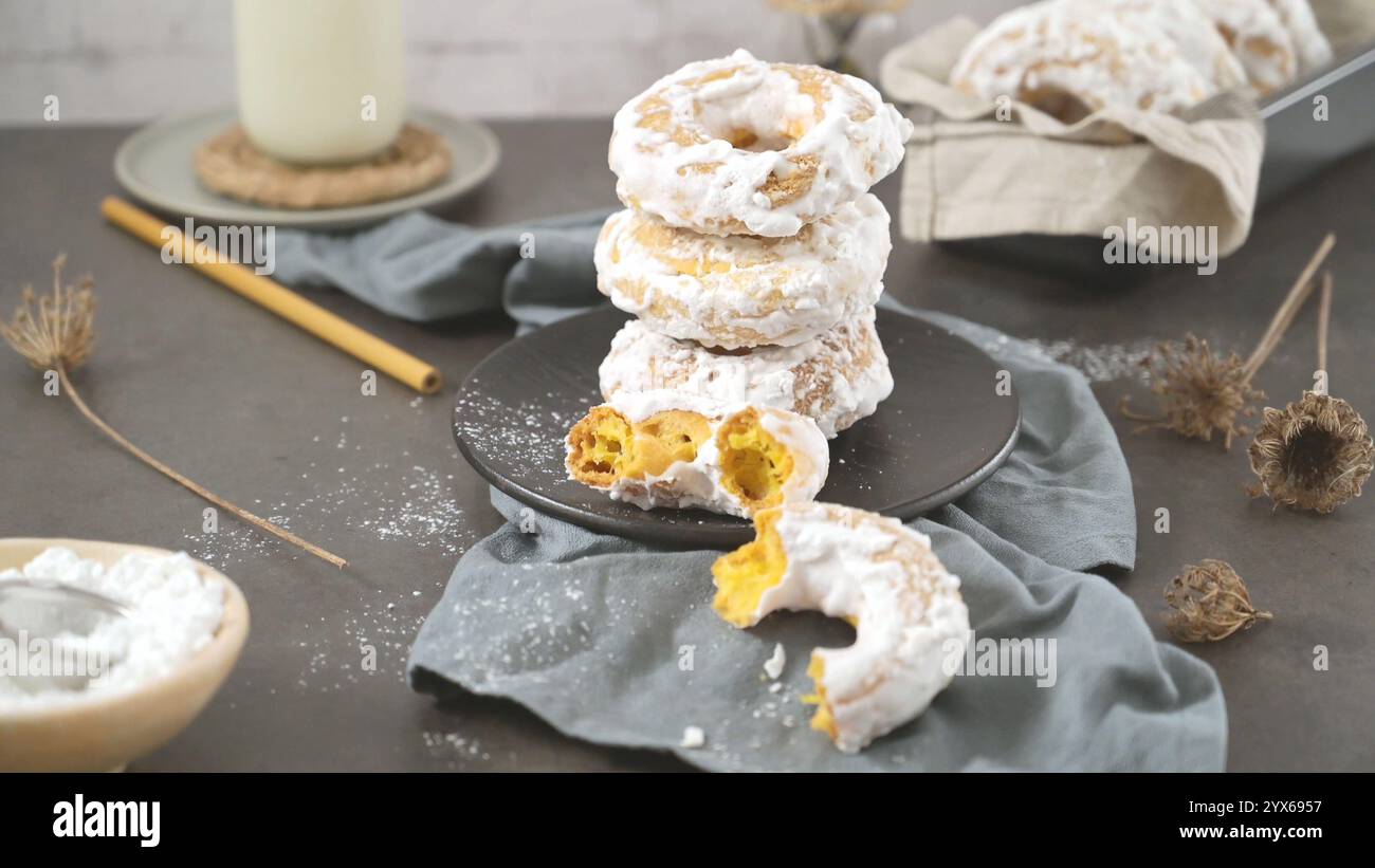 A stack of ring-shaped donuts dusted with powdered sugar, with one half ...