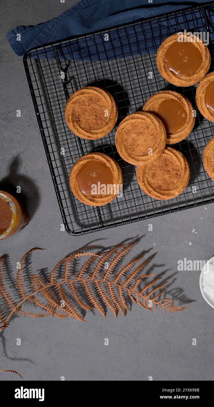 Caramel tarts on a cooling rack with a jar of caramel sauce, a bowl of ...