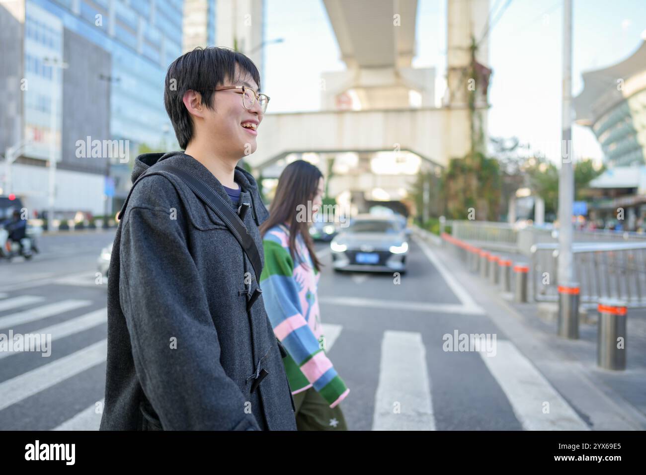 A young Chinese couple in their 20s walking on the sidewalk in Hongkou ...