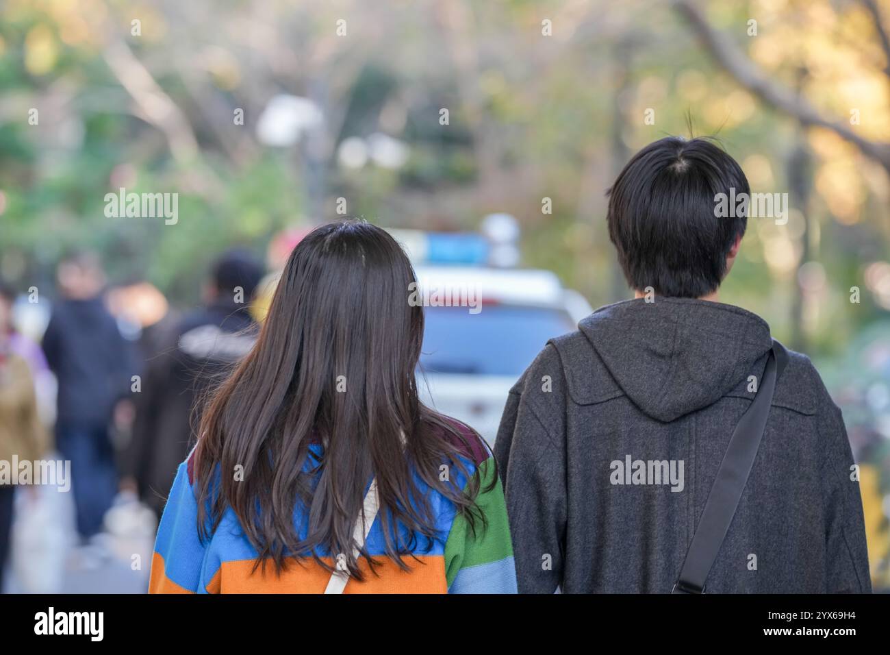 A young Chinese couple in their 20s walking on the sidewalk in Hongkou ...