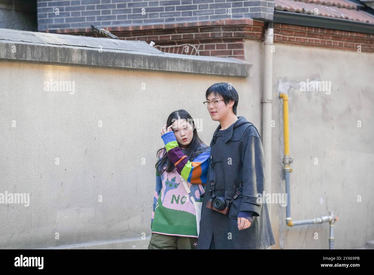 A young Chinese couple in their 20s walks on the sidewalk in Hongkou ...