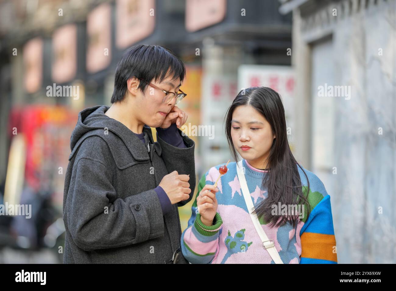 Young Chinese couple in their 20s eating Beijing's famous sugar-coated fruit sweets on a ...