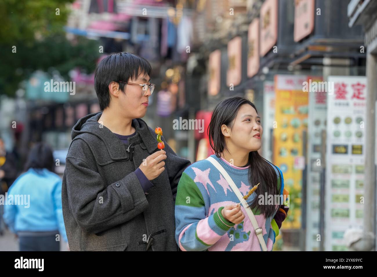 Young Chinese couple in their 20s eating Beijing's famous sugar-coated fruit sweets on a ...