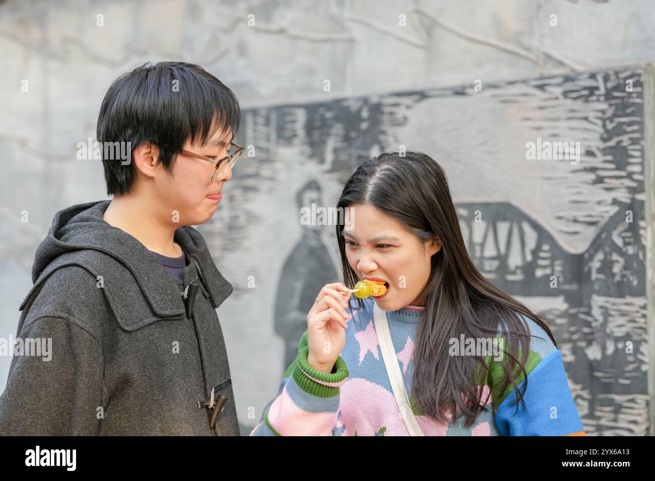 Young Chinese couple in their 20s eating Beijing's famous sugar-coated fruit sweets on a ...