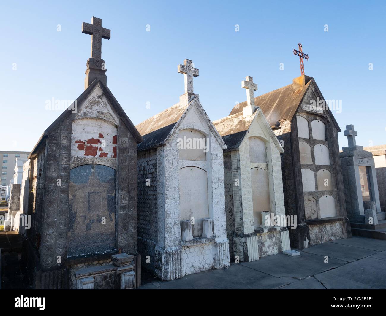 Weathered, narrow, above ground burial crypts topped with crosses in ...