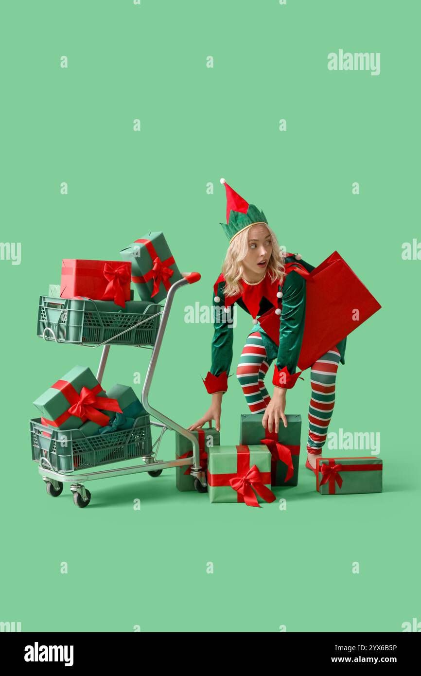 Beautiful young woman dressed as elf with shopping cart and Christmas ...