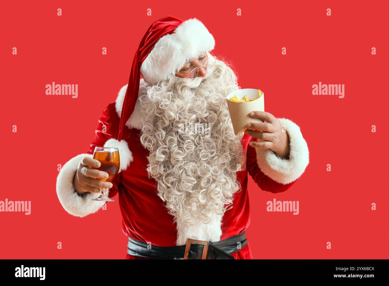 Santa Claus with glass of beer and tasty french fries on red background ...