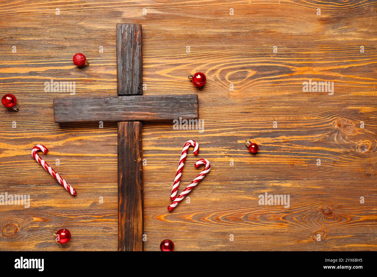 Cross with balls and candy canes on wooden background. Christmas story ...
