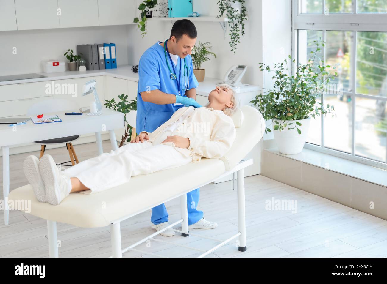 Male endocrinologist examining thyroid gland of female patient on couch ...
