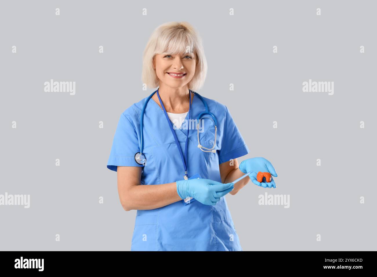 Female endocrinologist with thyroid gland model on light background ...