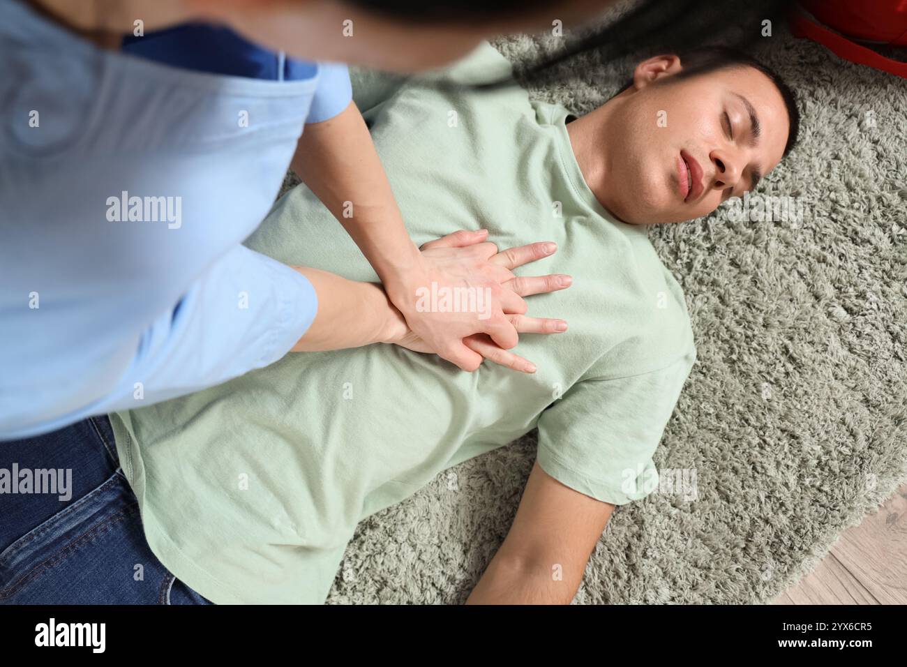 Female doctor doing CPR on unconscious man having heart attack at home, top view Stock Photo - Alamy