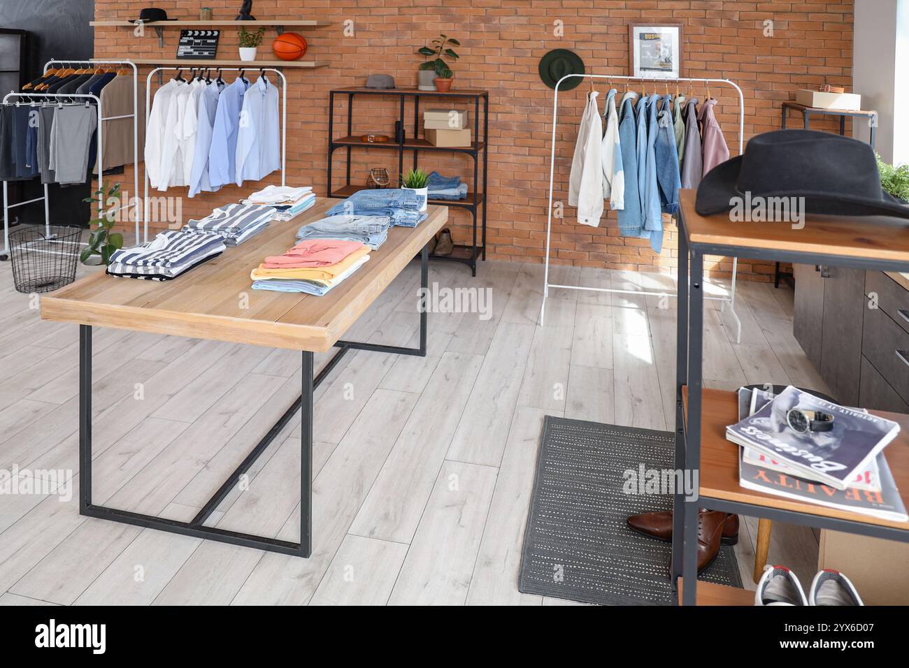 Interior of men's clothing store with racks, shelf units and table ...
