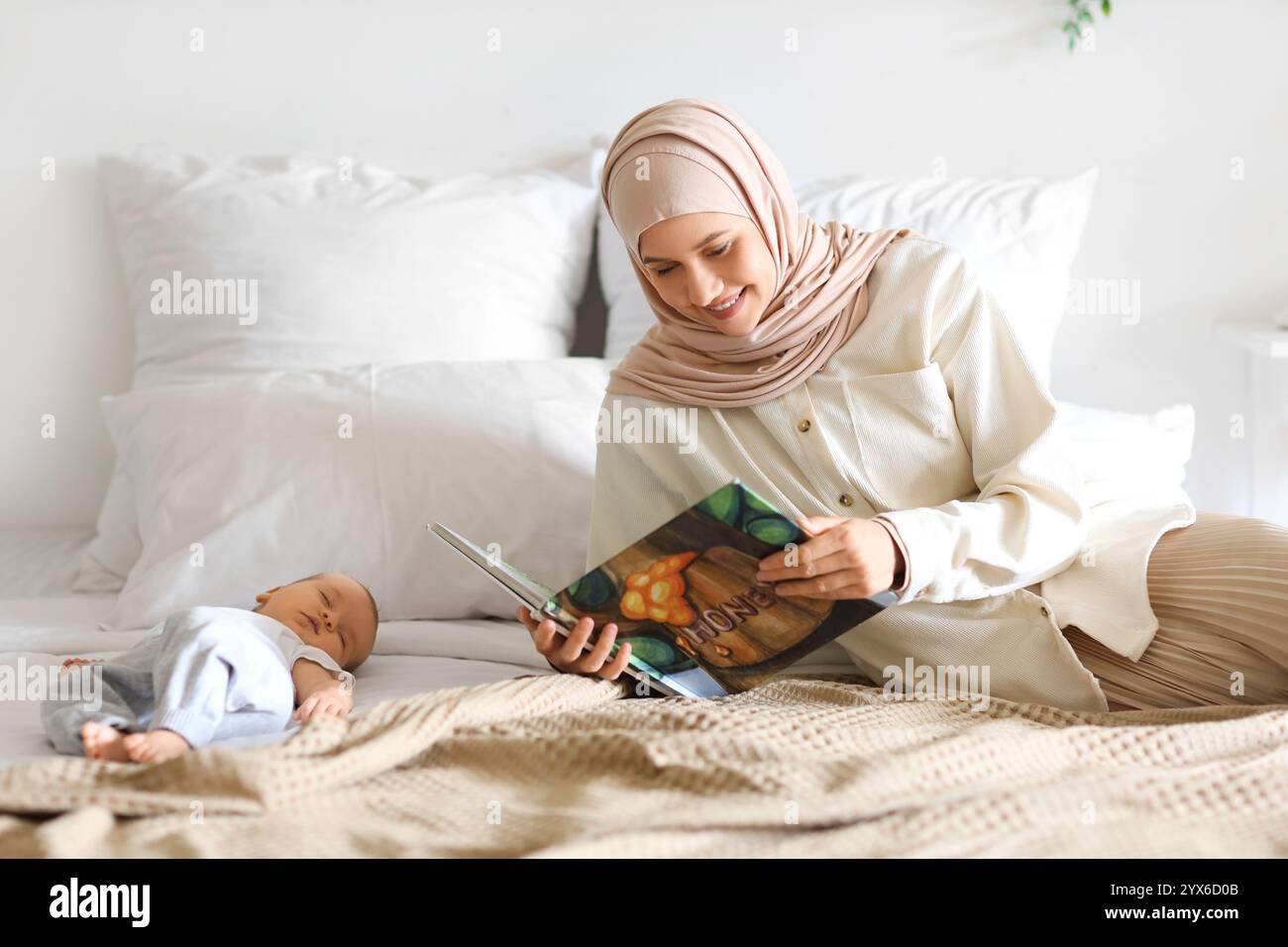 Happy Muslim mother in hijab reading book while her cute little baby ...