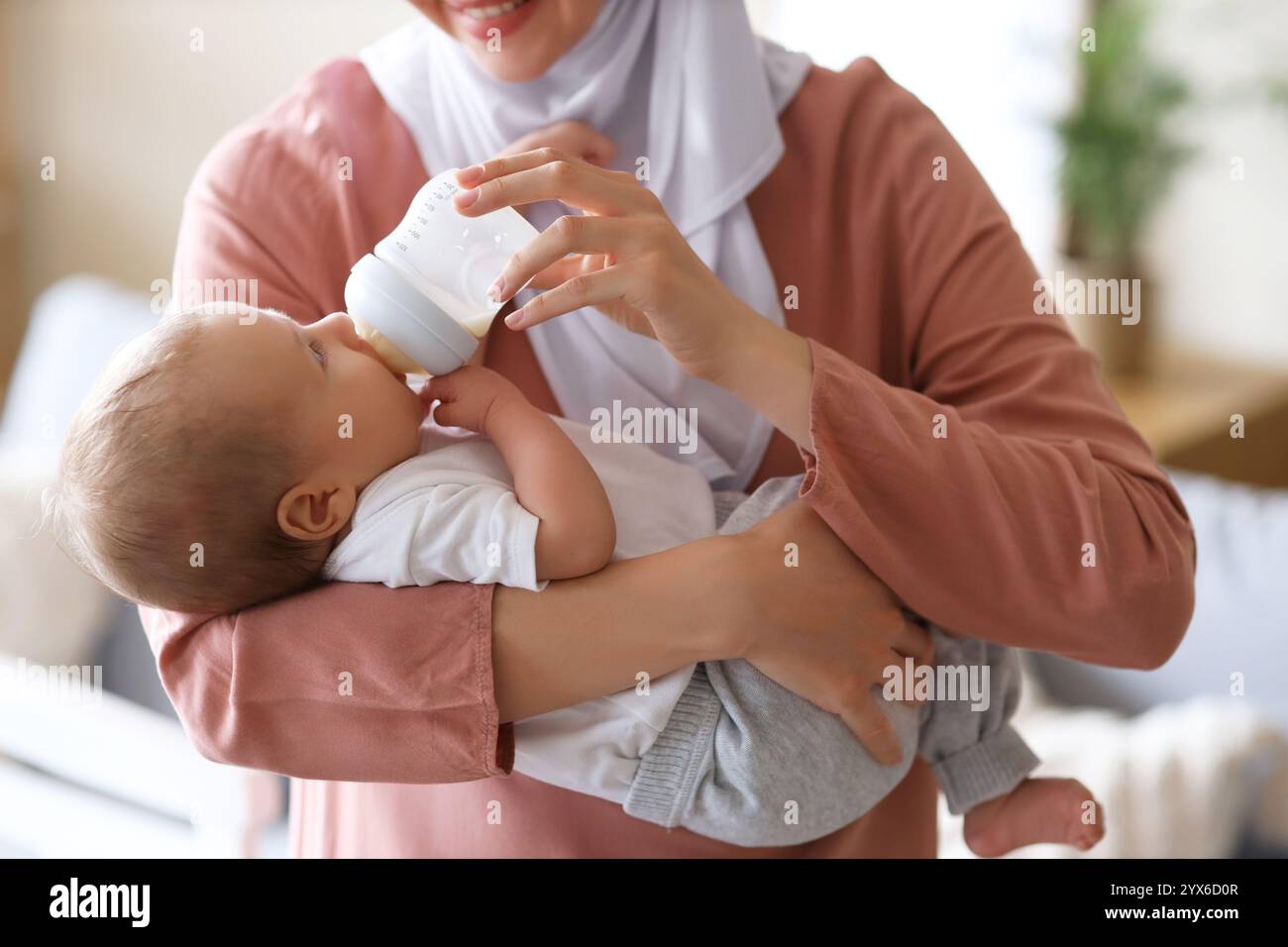 Muslim mother in hijab feeding her cute little baby with milk from ...
