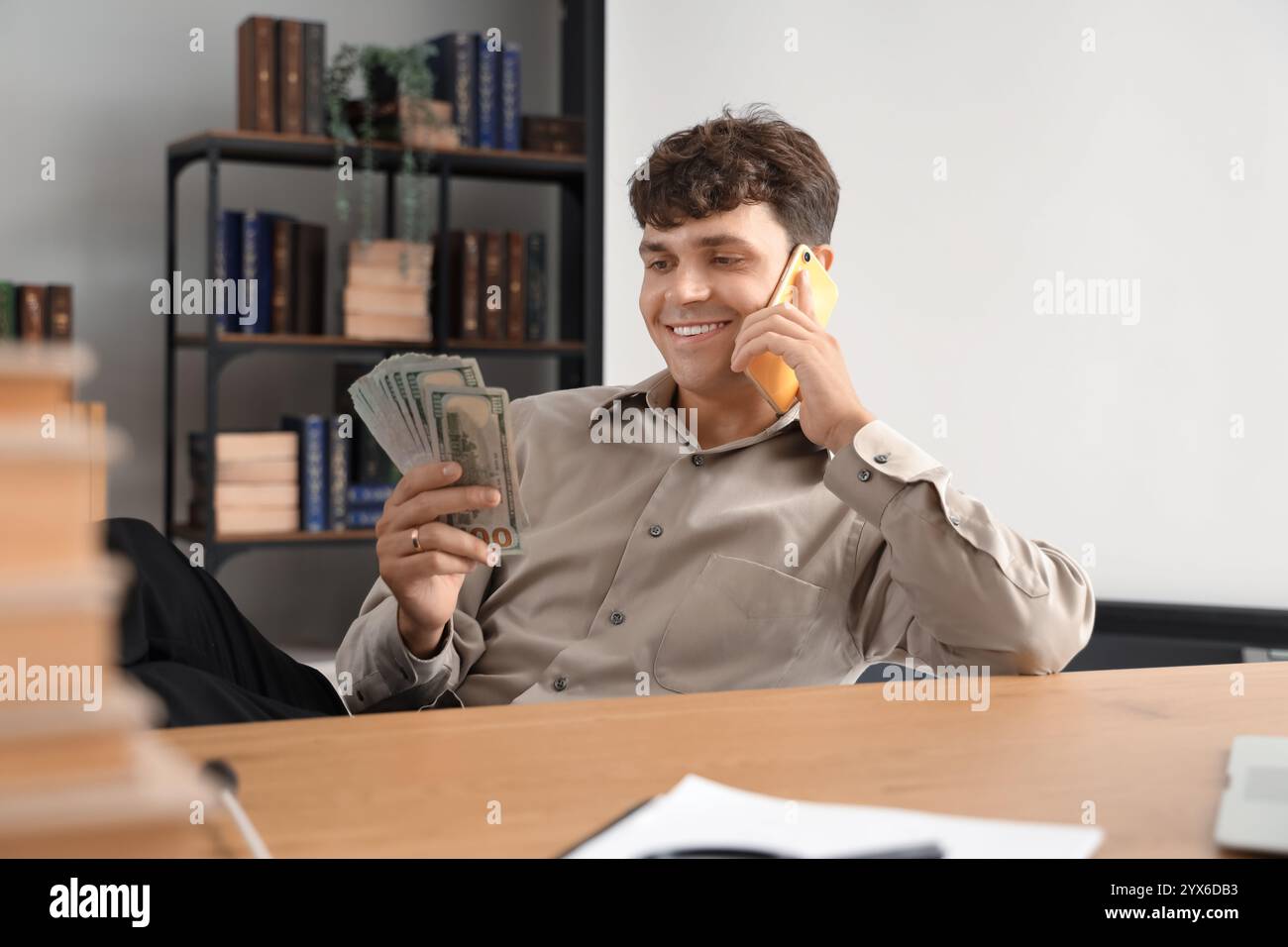 Male teacher with bribe talking by mobile phone in classroom ...