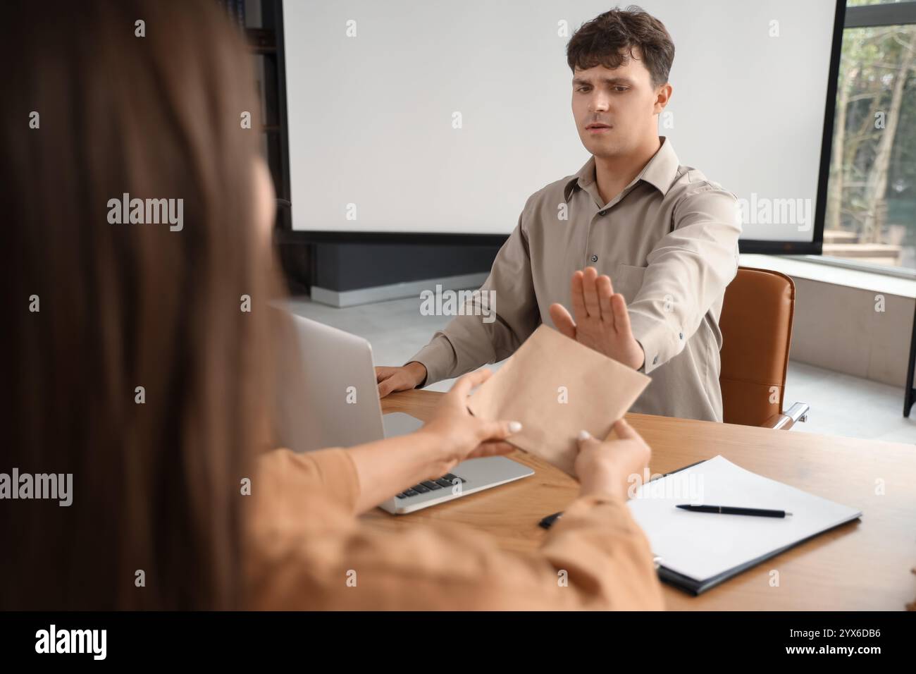 Male teacher refusing to take bribe at table in classroom. Corruption ...