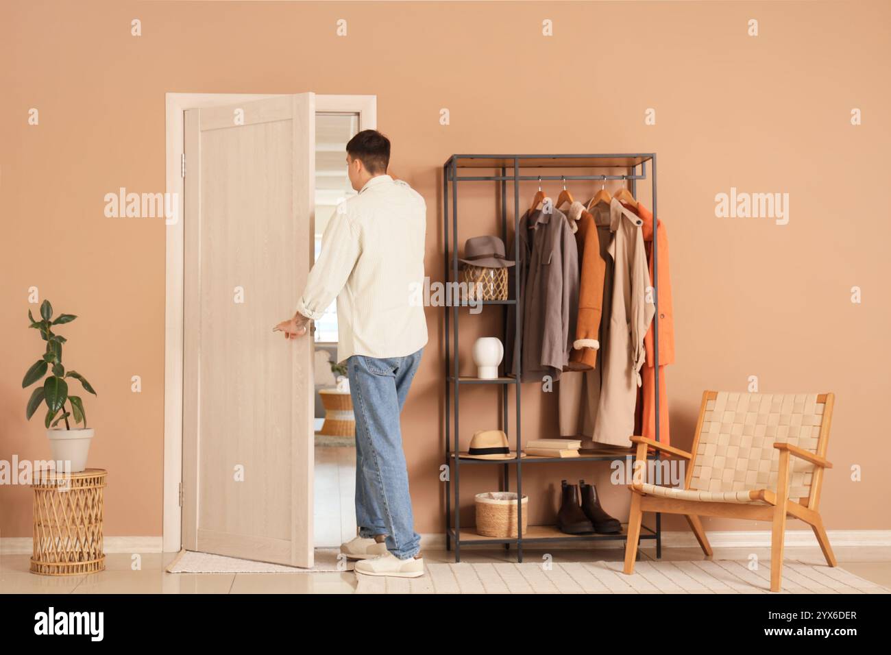 Young man walking through door in hall, back view Stock Photo - Alamy