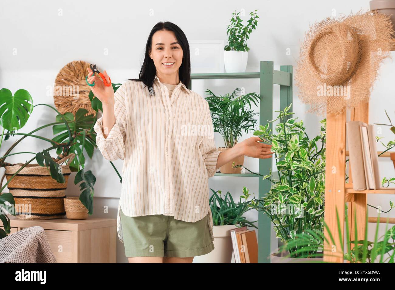 Beautiful young woman with pruner and houseplants at home Stock Photo ...