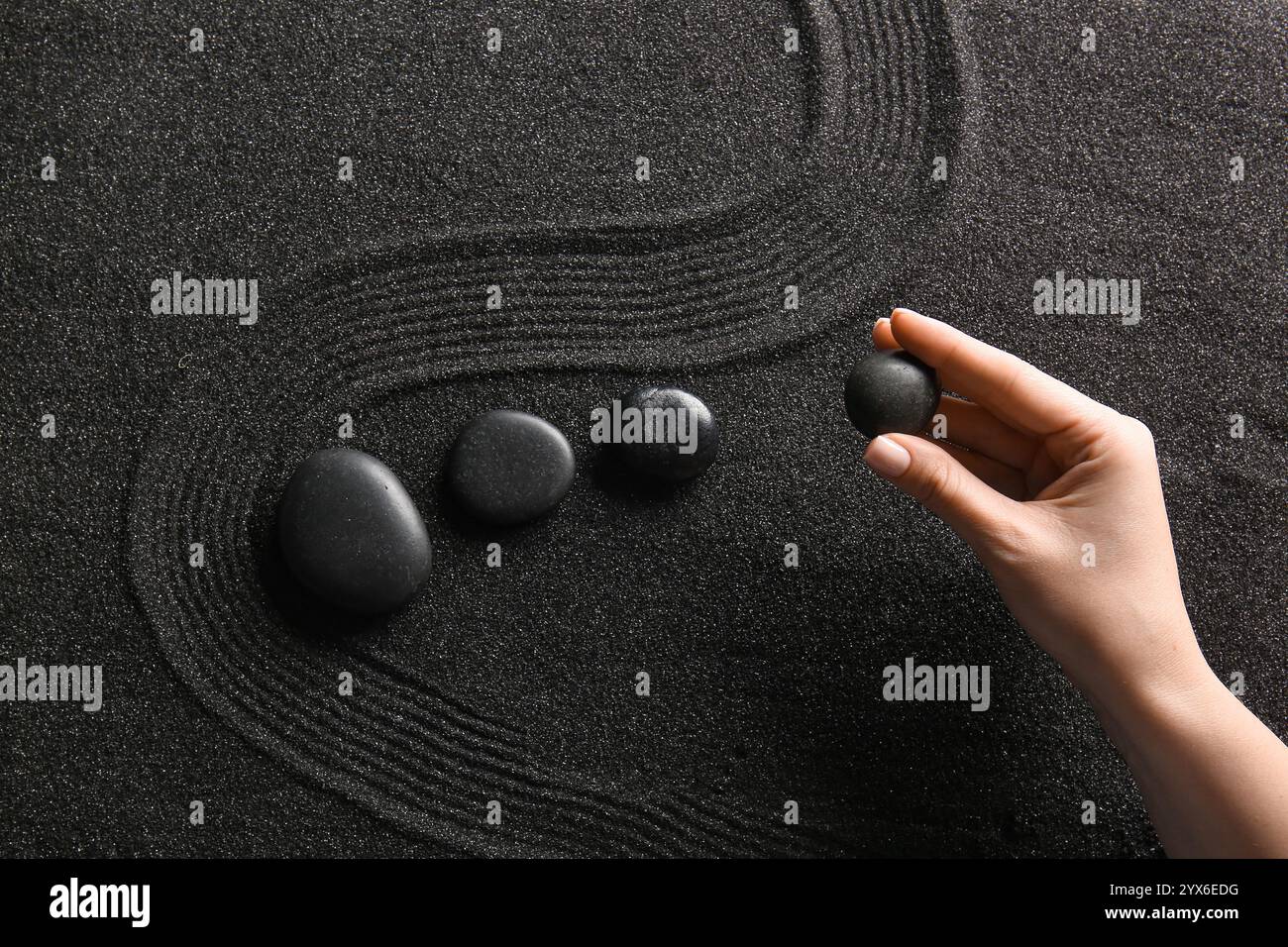 Female hand and stones on black sand with lines. Zen concept Stock ...