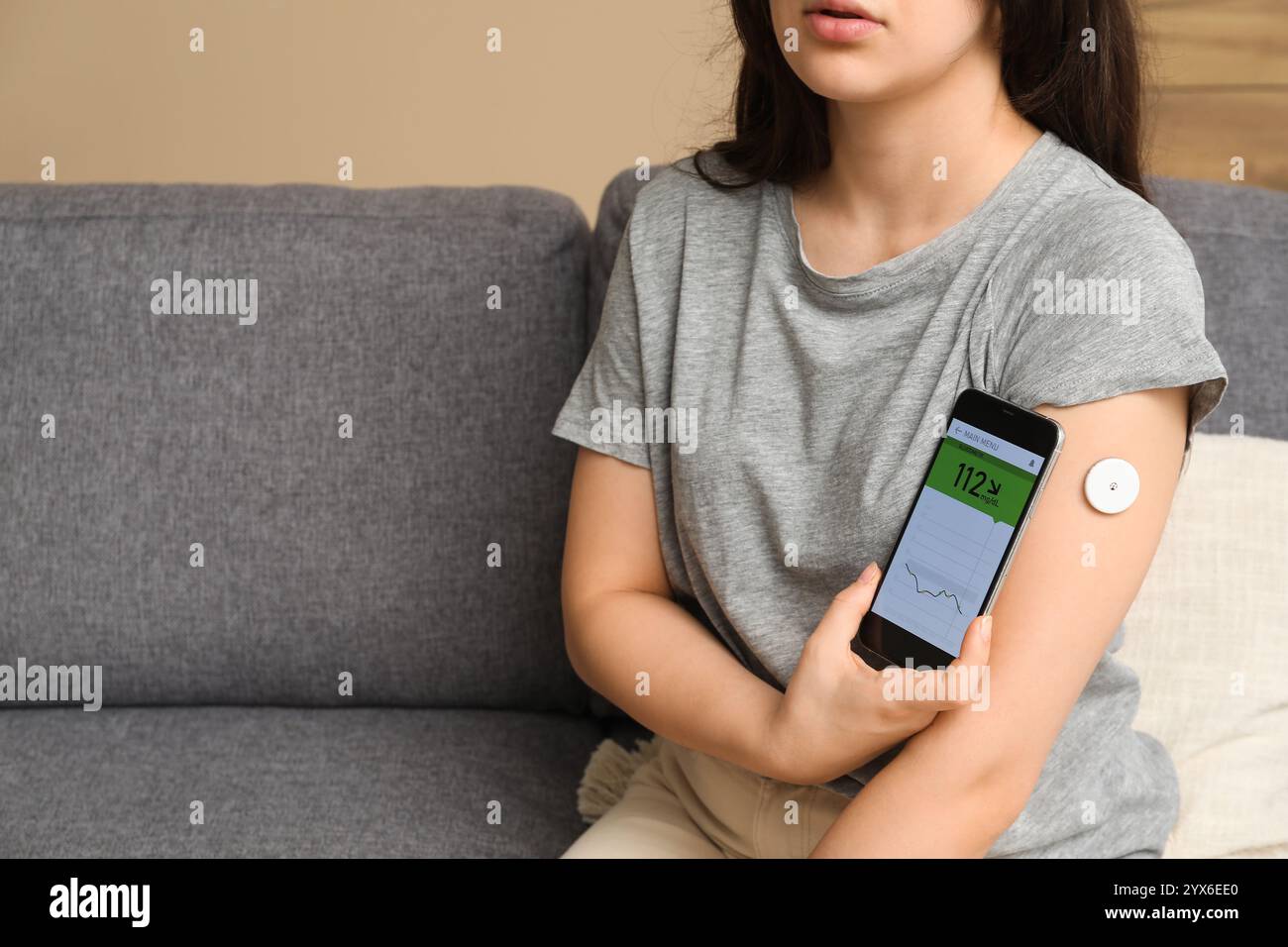 Diabetic young woman with glucose sensor using mobile phone for ...