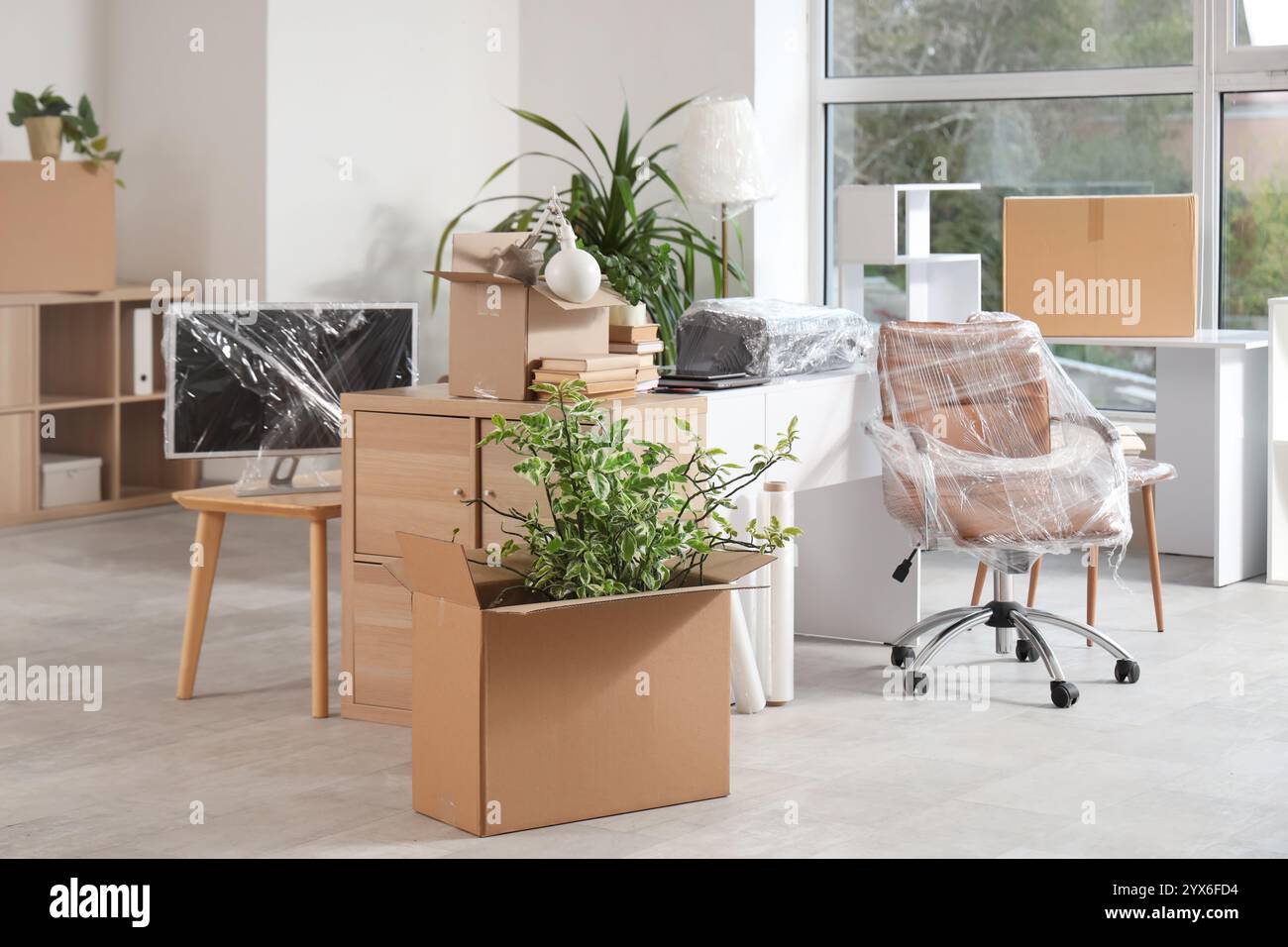 Interior of office with desk, boxes and wrapped chair in stretch film ...