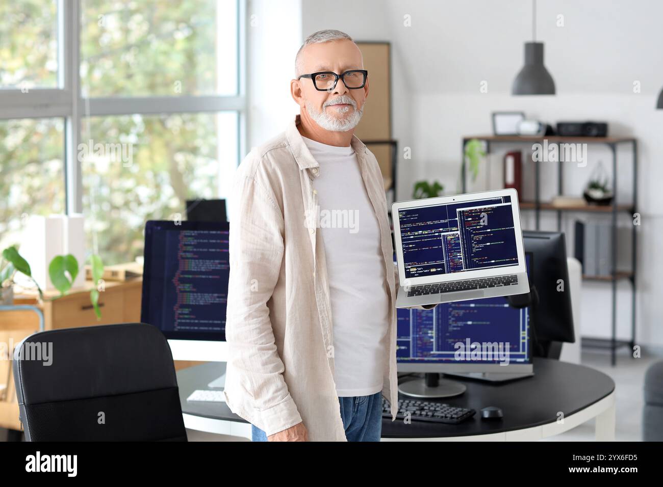 Mature programmer with laptop in office Stock Photo - Alamy