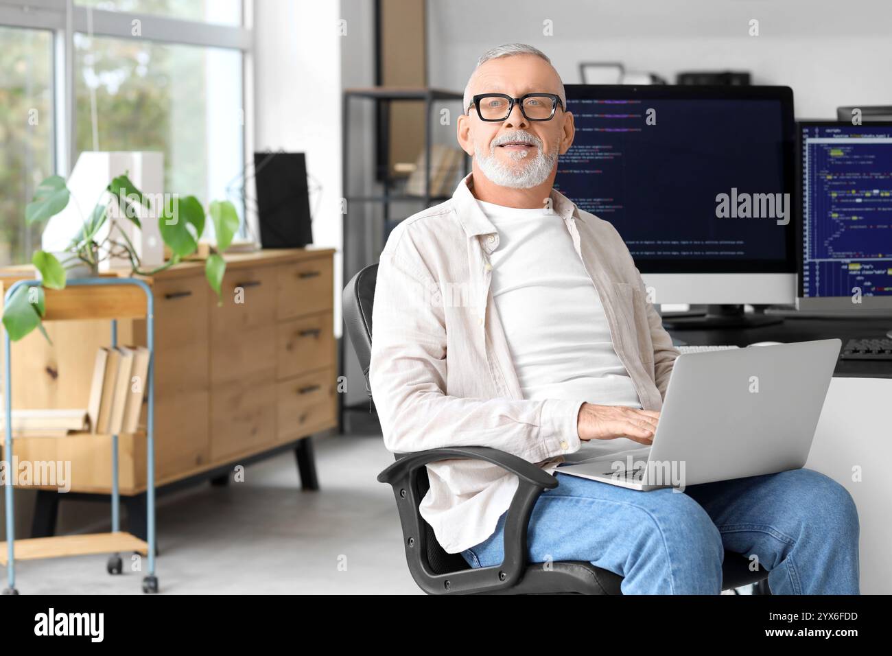 Mature programmer working with laptop in office Stock Photo - Alamy