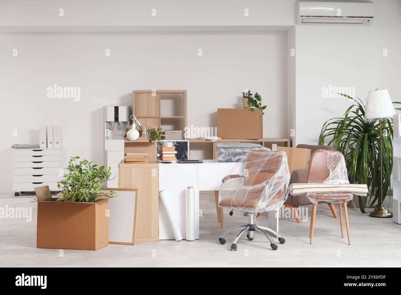 Interior of office with desk, boxes and wrapped chairs in stretch film ...