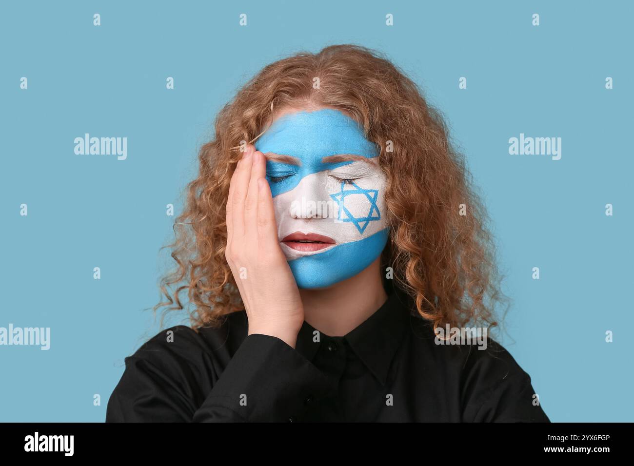 Young woman with painted flag of Israel on her face against blue ...