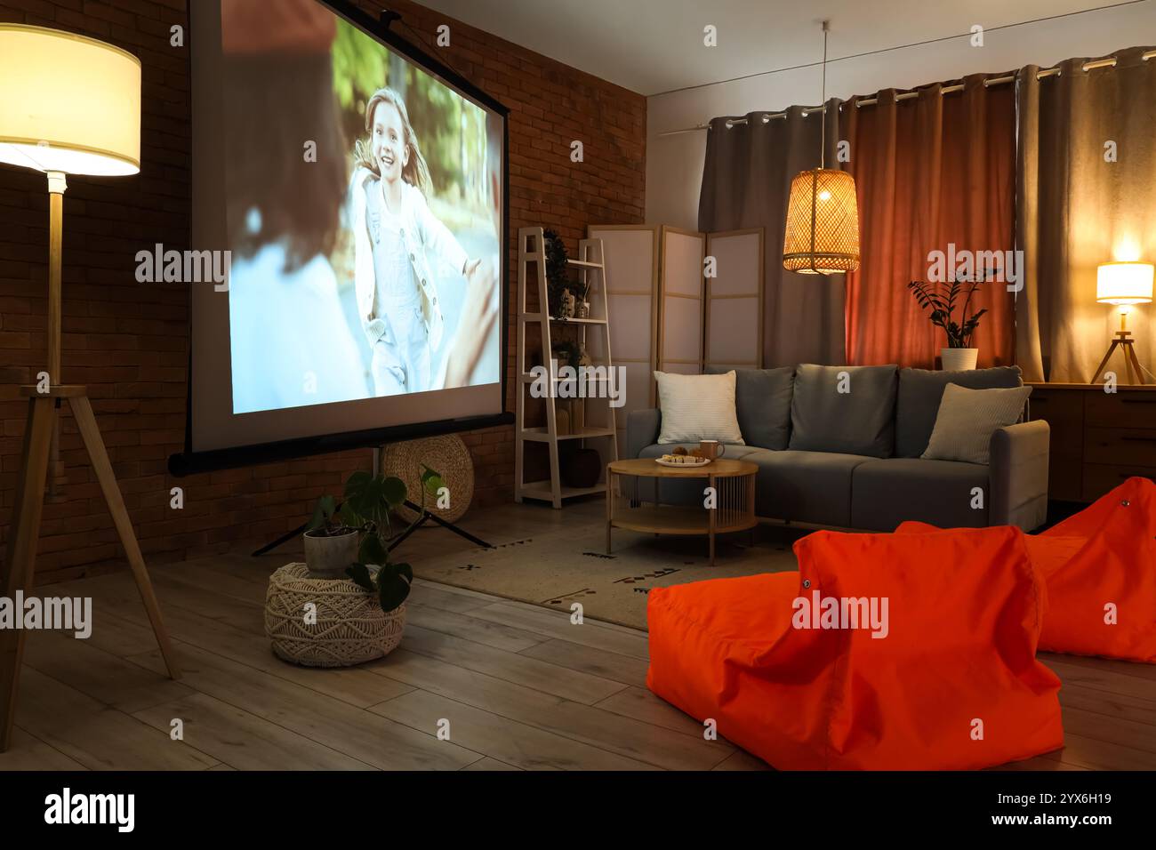Interior of dark living room with projector screen, sofa and beanbags ...