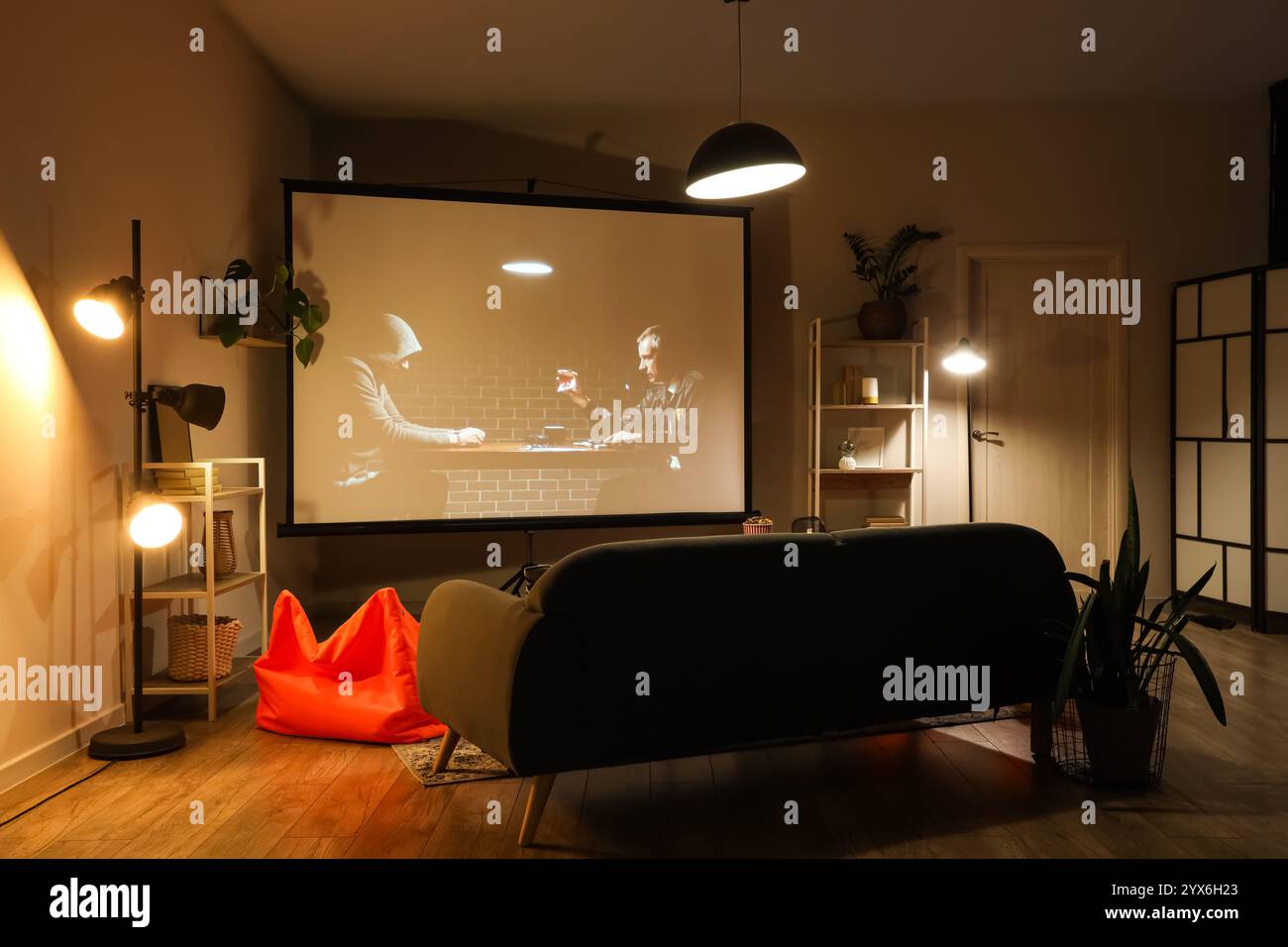 Interior of dark living room with projector screen, sofa and beanbag at ...
