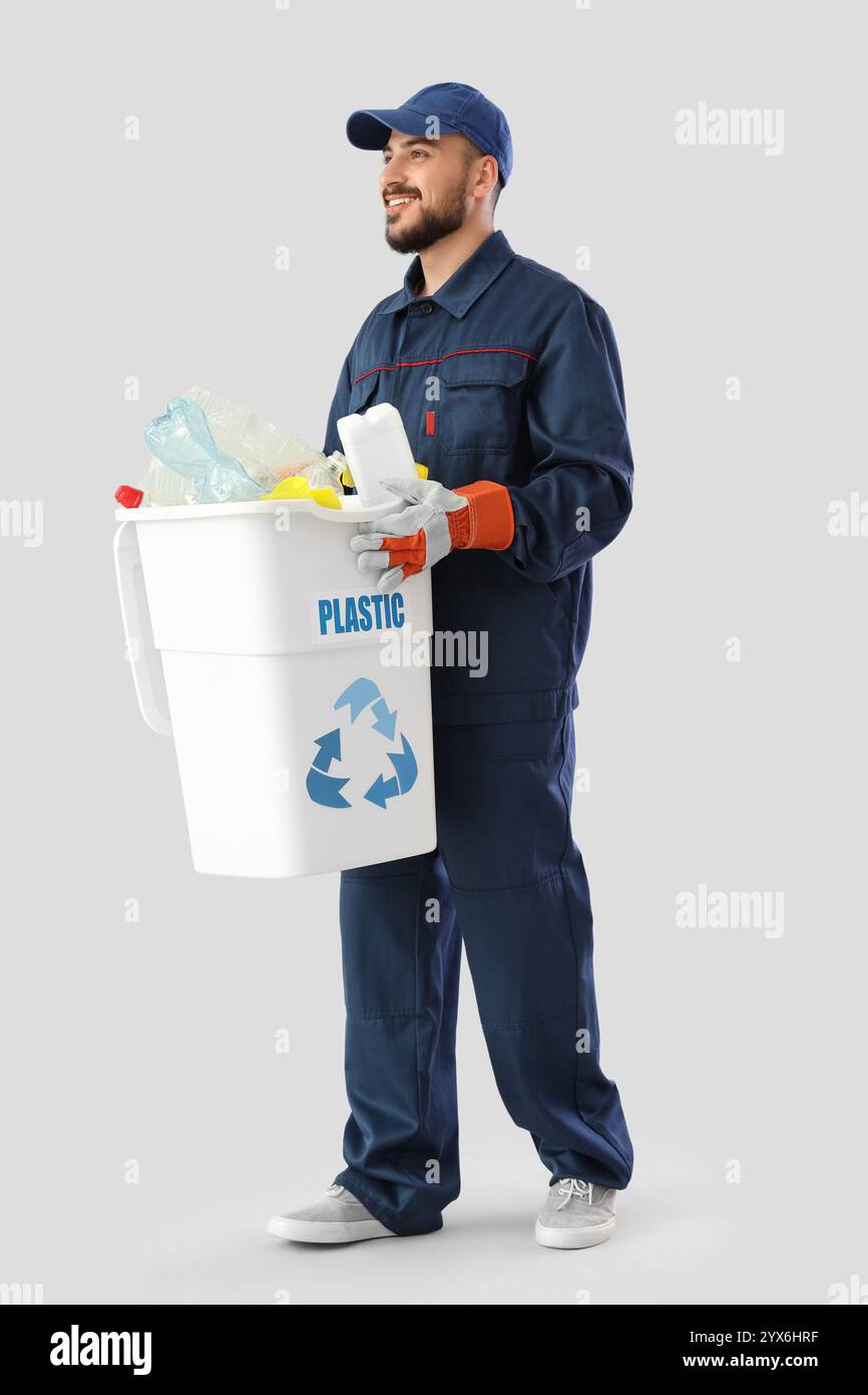 Male scavenger holding recycle trash bin with plastic on light ...