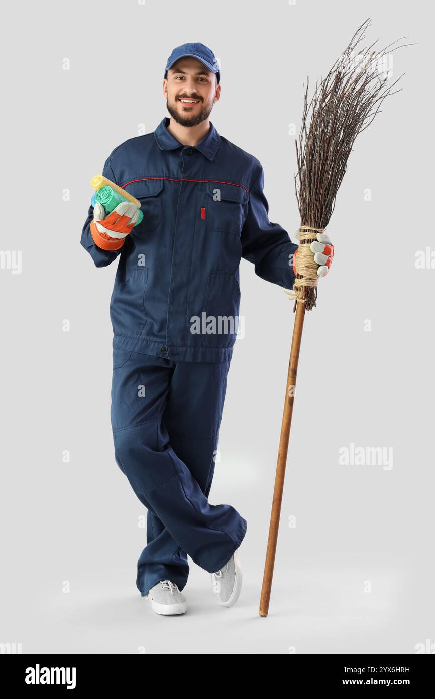 Male scavenger with garbage bags and broom on light background Stock ...
