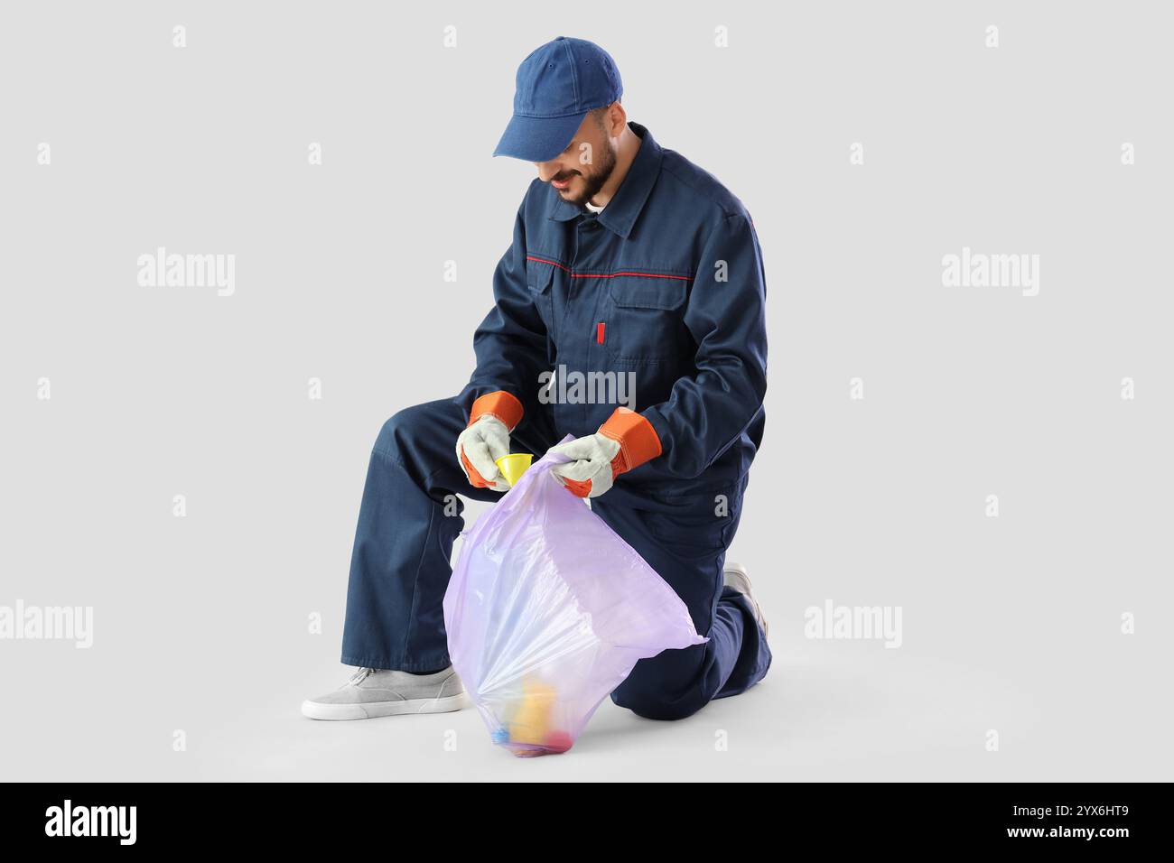 Male scavenger throwing garbage into bag on light background Stock ...