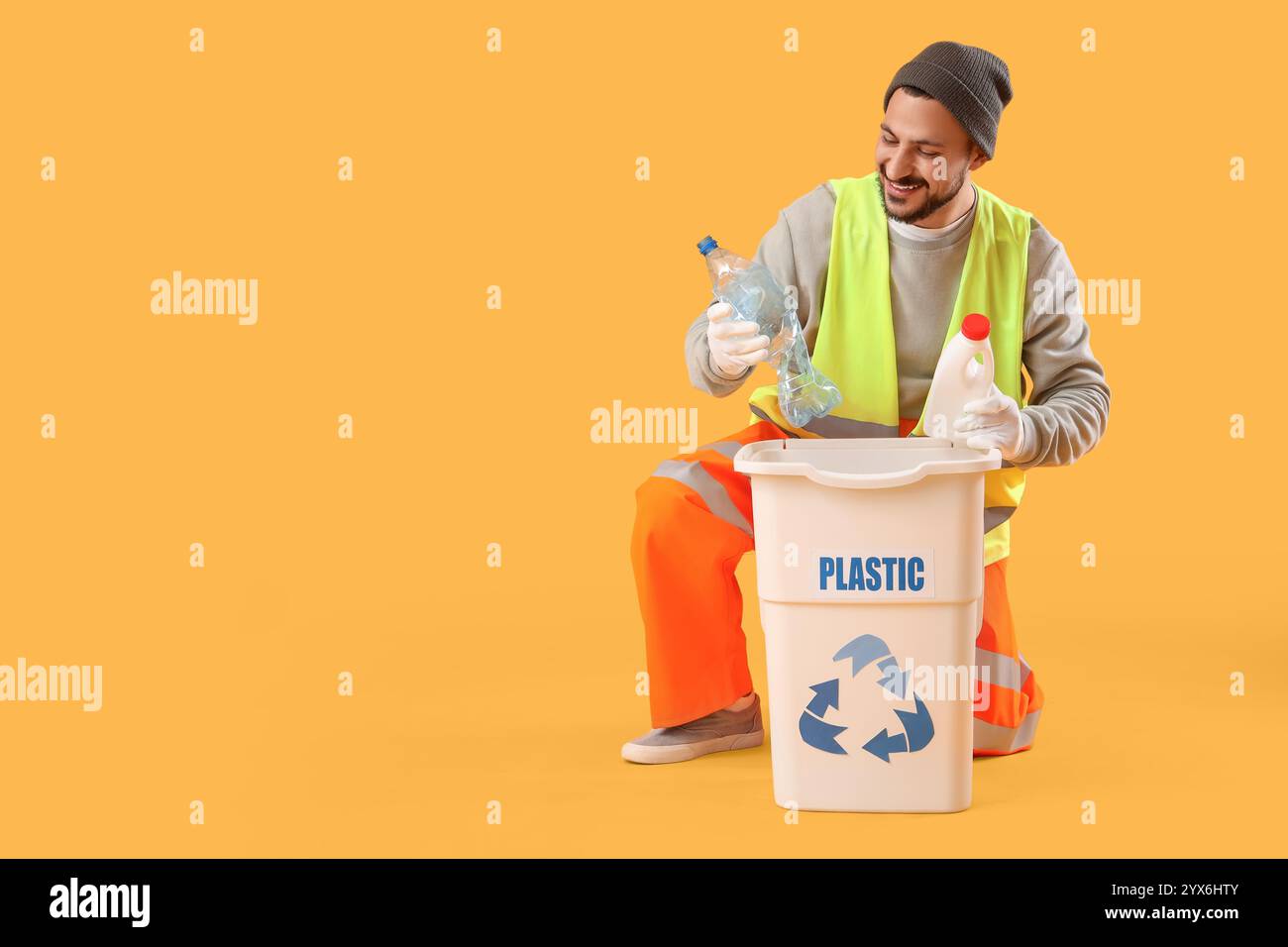 Male scavenger throwing plastic bottles into trash bin on yellow ...