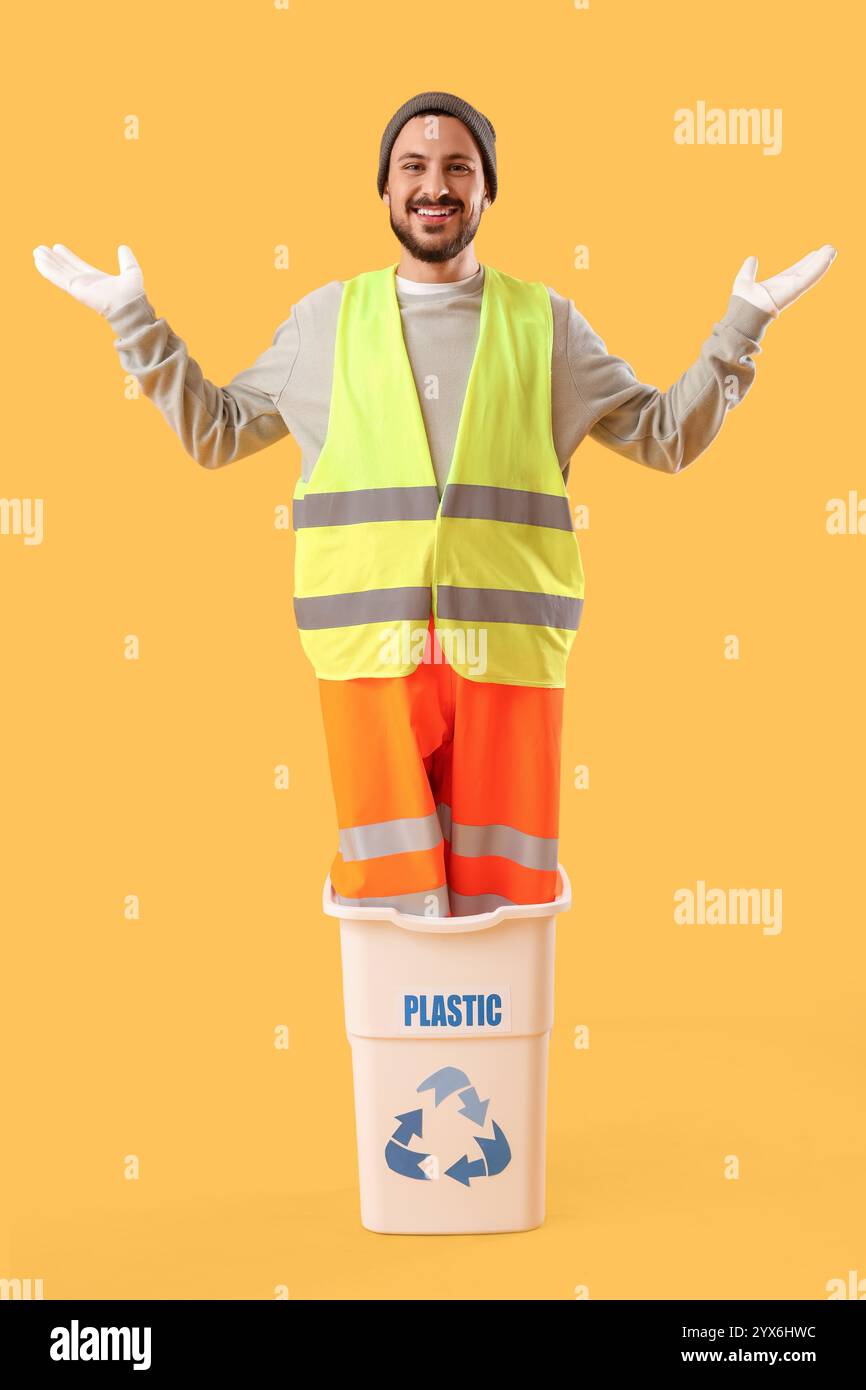 Male scavenger in recycle trash bin for plastic on yellow background ...