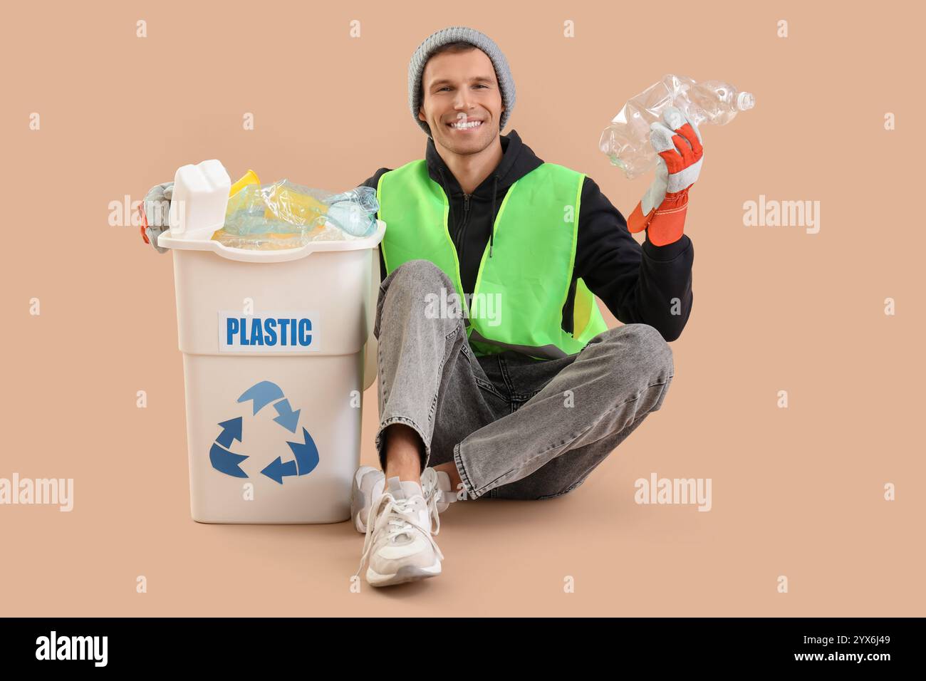 Male scavenger with plastic garbage and recycle bin sitting on beige ...