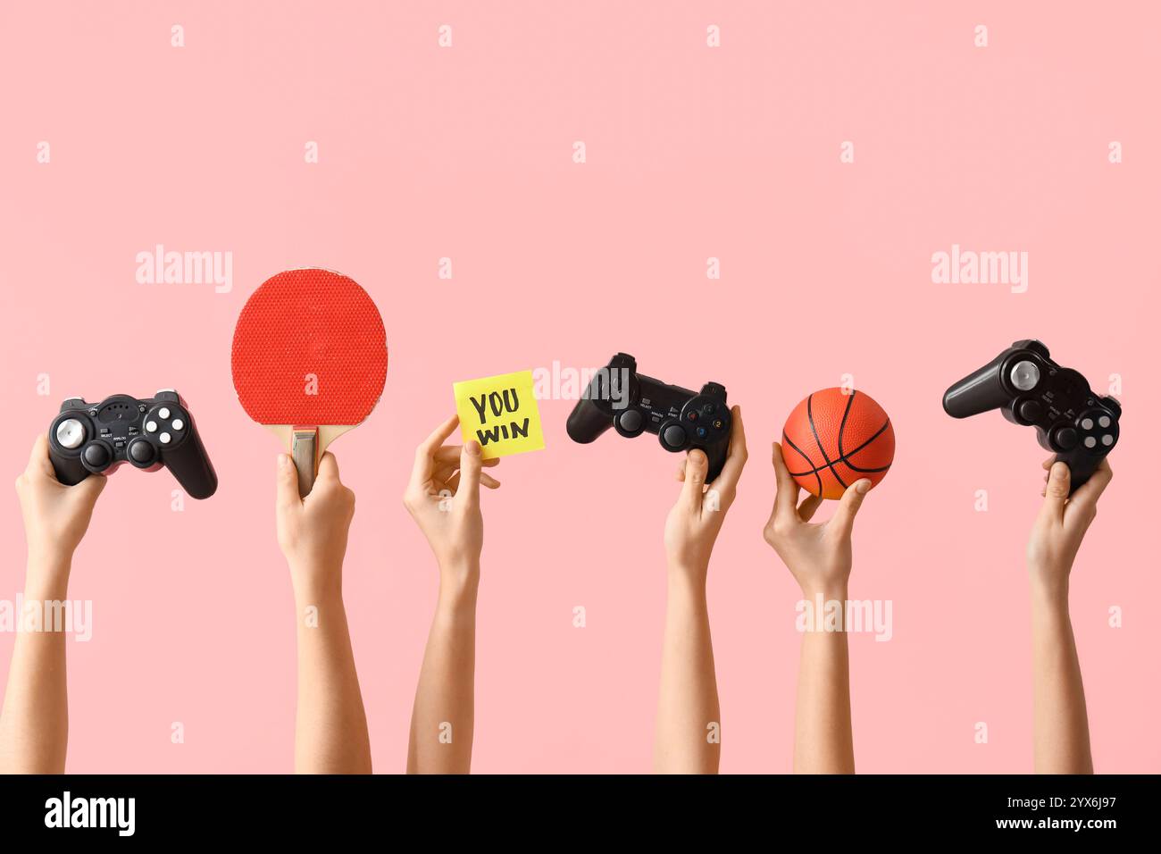 Female hands with game pads, ping pong racket and ball on pink ...