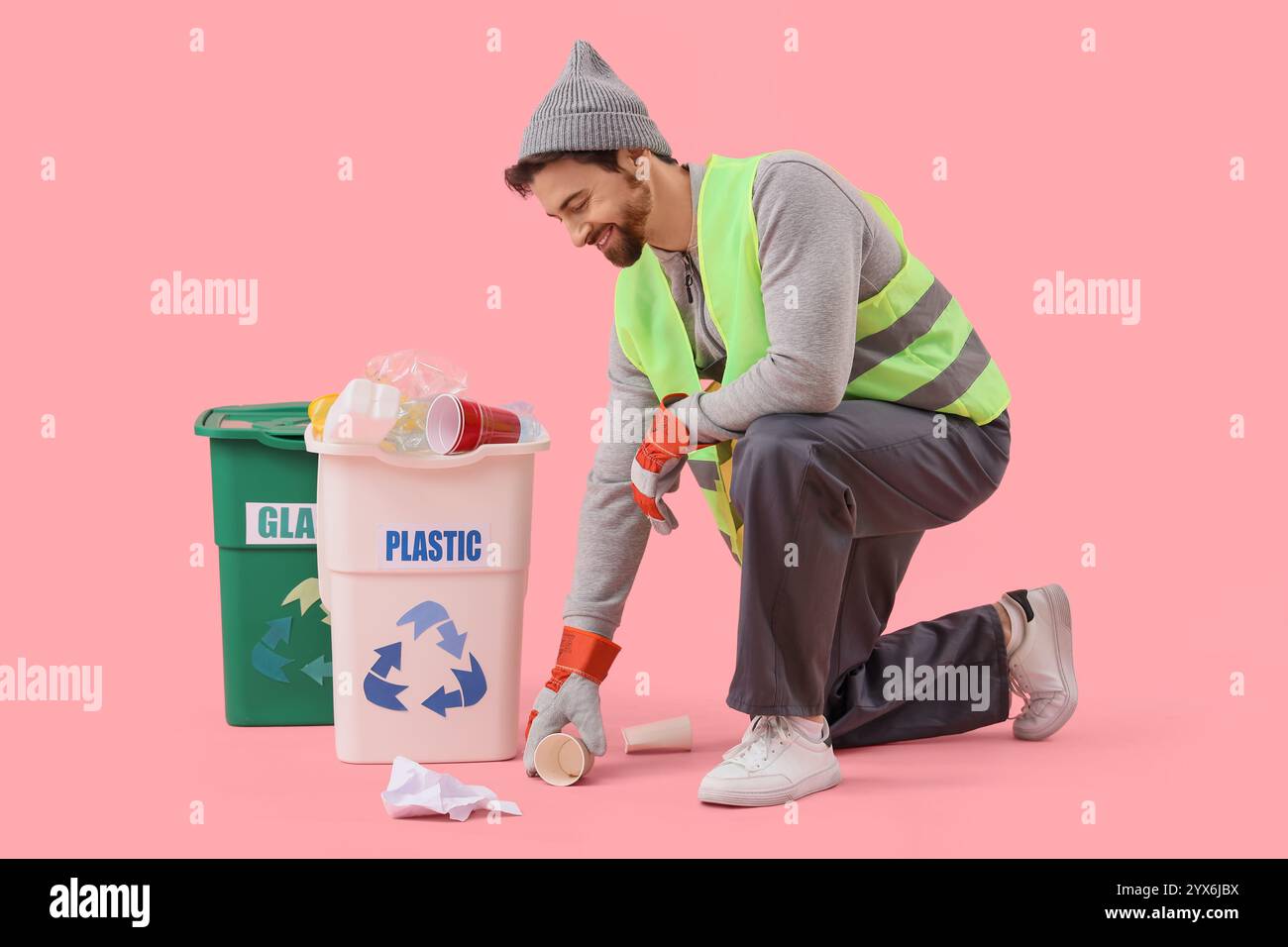 Male scavenger with garbage and trash bins on pink background Stock ...
