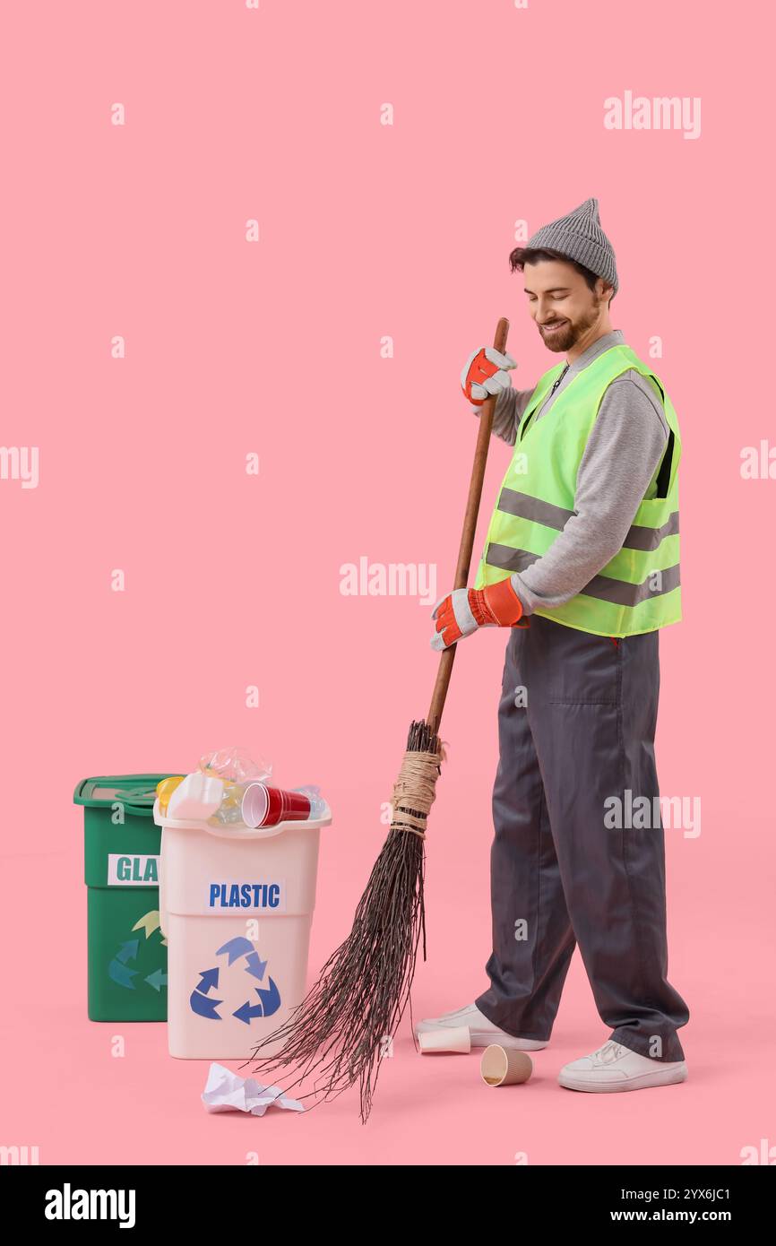 Male scavenger with broom and trash bins on pink background Stock Photo ...