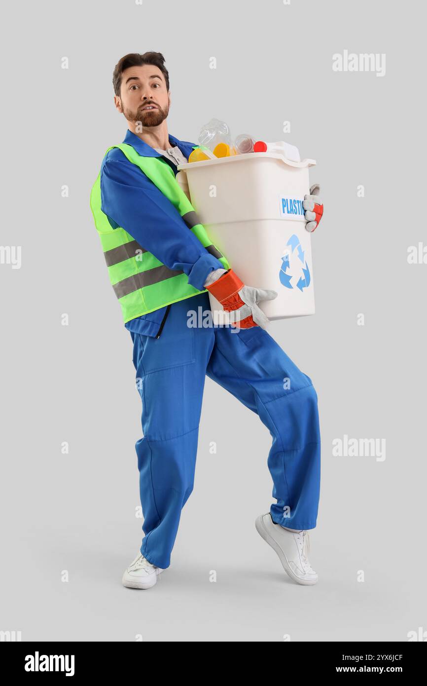 Shocked male scavenger carrying trash bin with plastic garbage on light ...