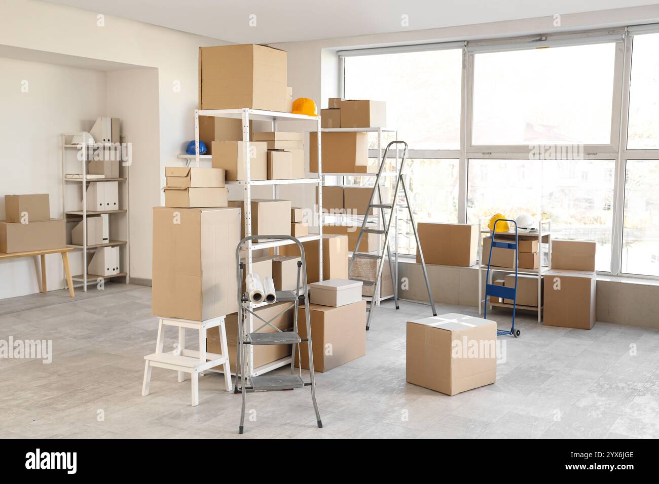 Interior of warehouse with shelf units, cardboard boxes and stepladders ...