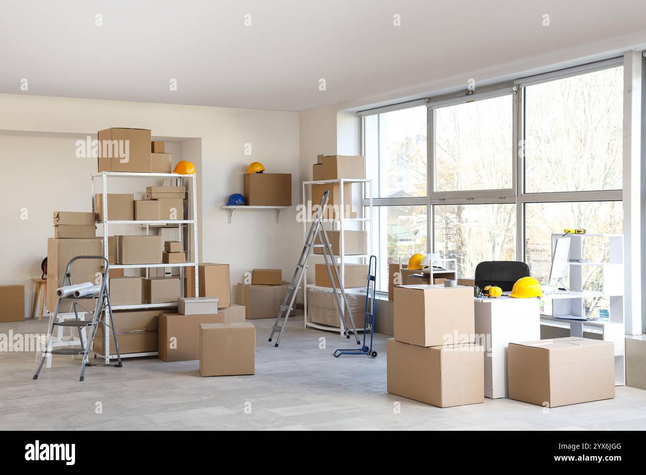 Interior of warehouse with shelf units, cardboard boxes and stepladders ...