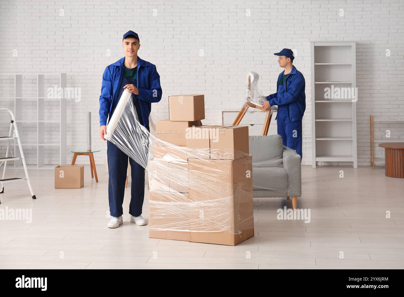 Male worker wrapping cardboard boxes with stretch film in room Stock ...